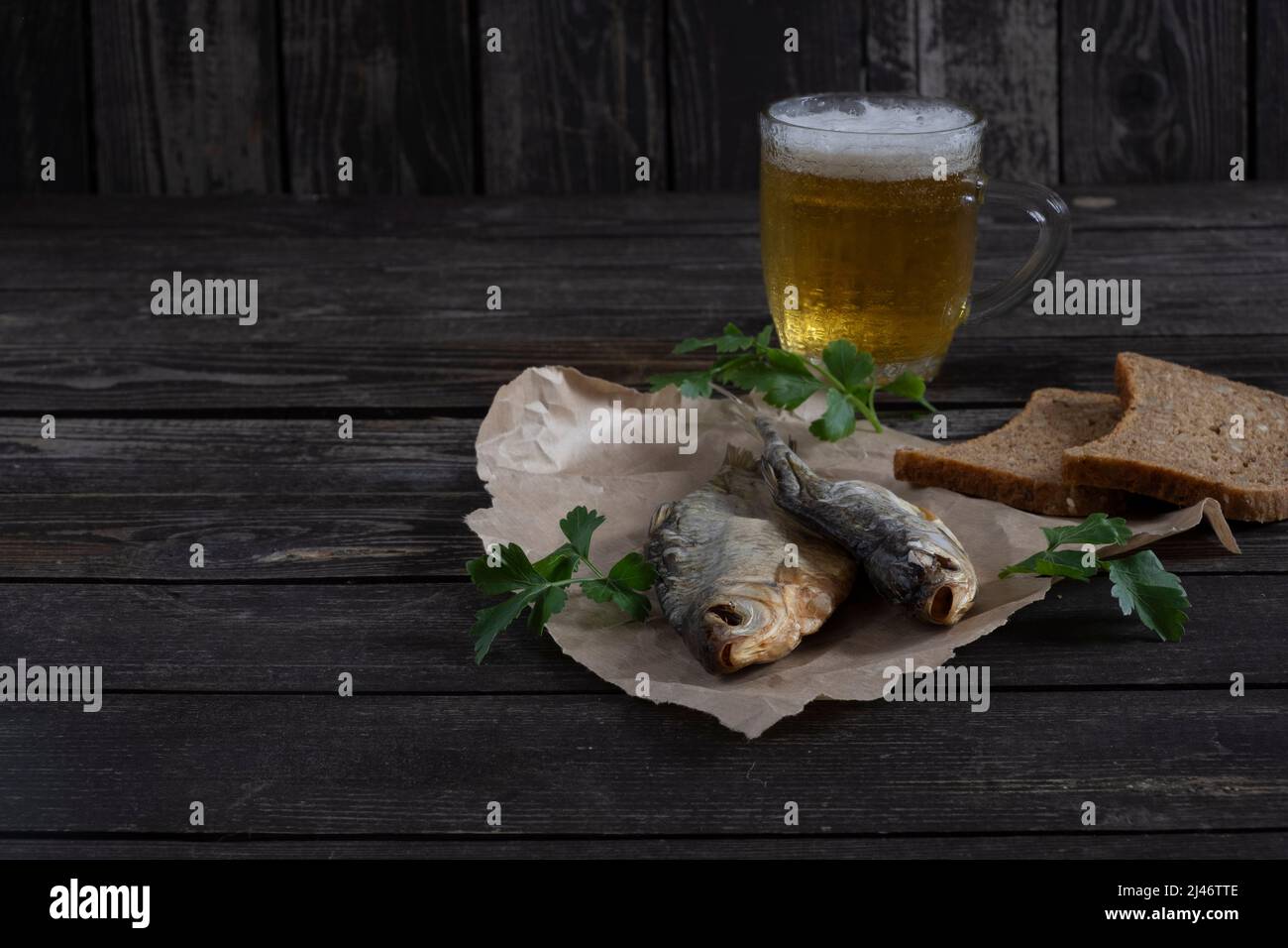 salted, dried vobla fish with amber beer on dark wooden background with ...