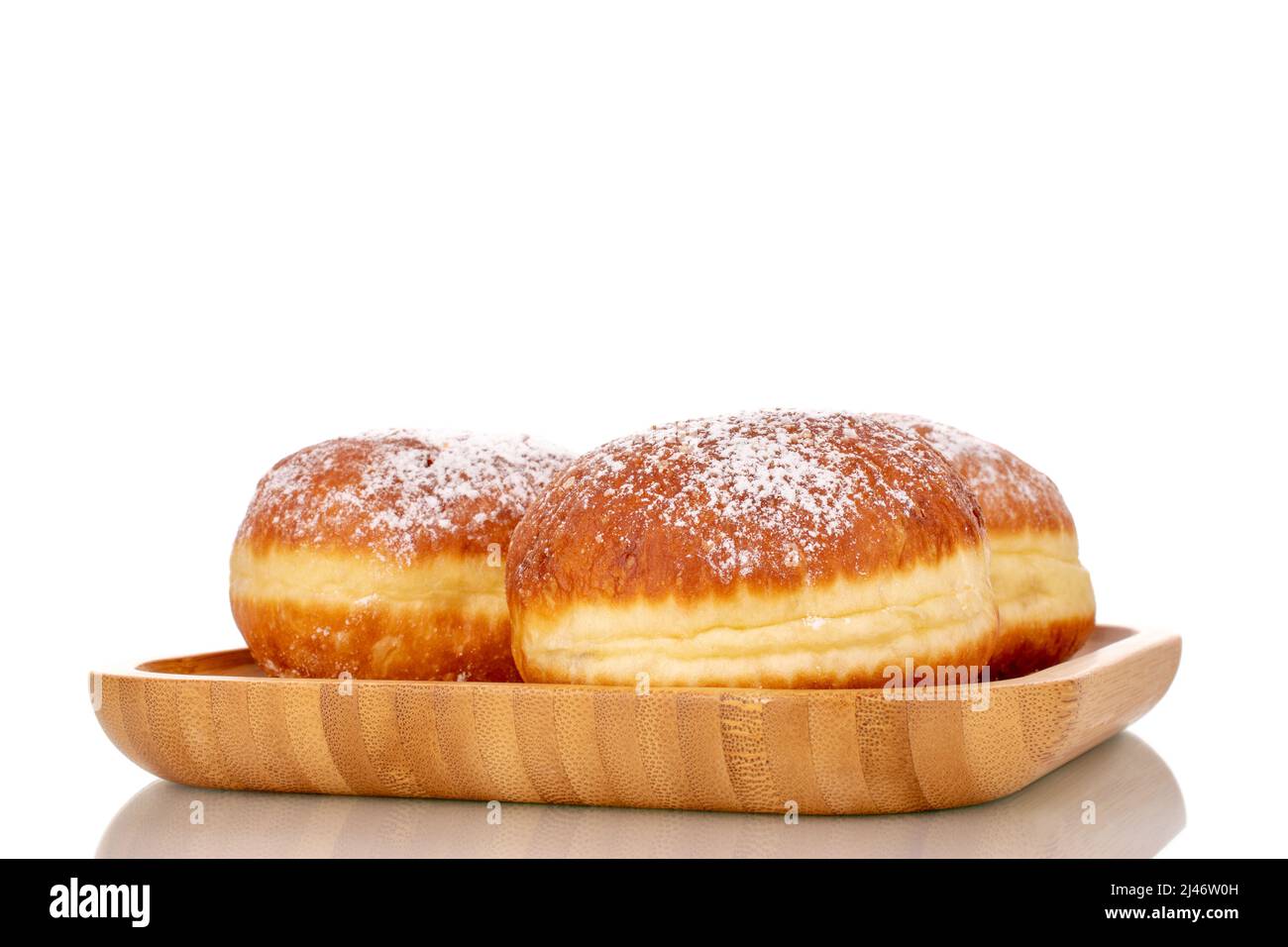 Three sweet donuts stuffed with jam on a bamboo tray, close-up ...