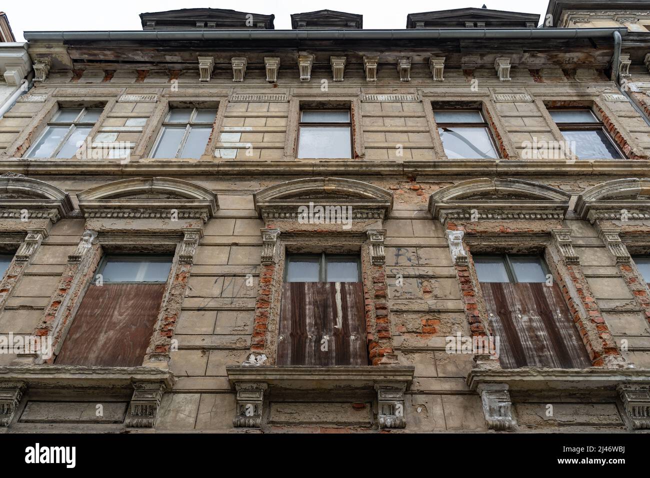 Facade of an old abandoned house. Looking up to the roof gutter. Architecture of an historic ...