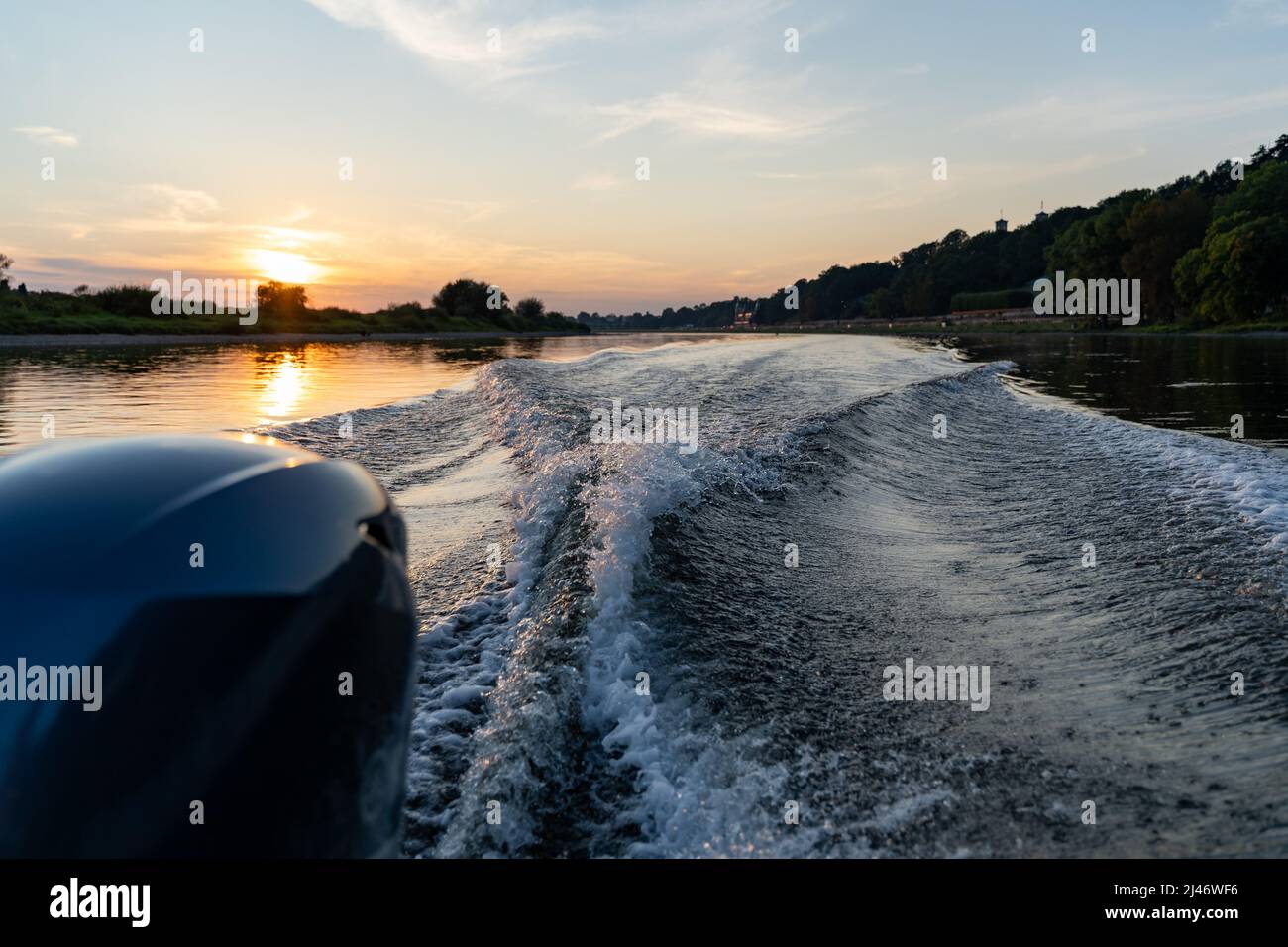 Water waves behind a motorboat on a river. Sunset light in the evening ...