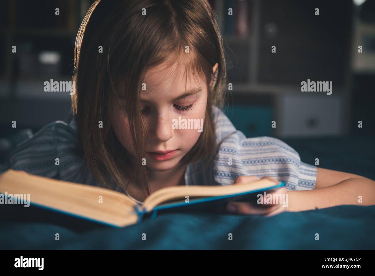 cute girl reading a book at home, lying on the bed. home pastime Stock ...