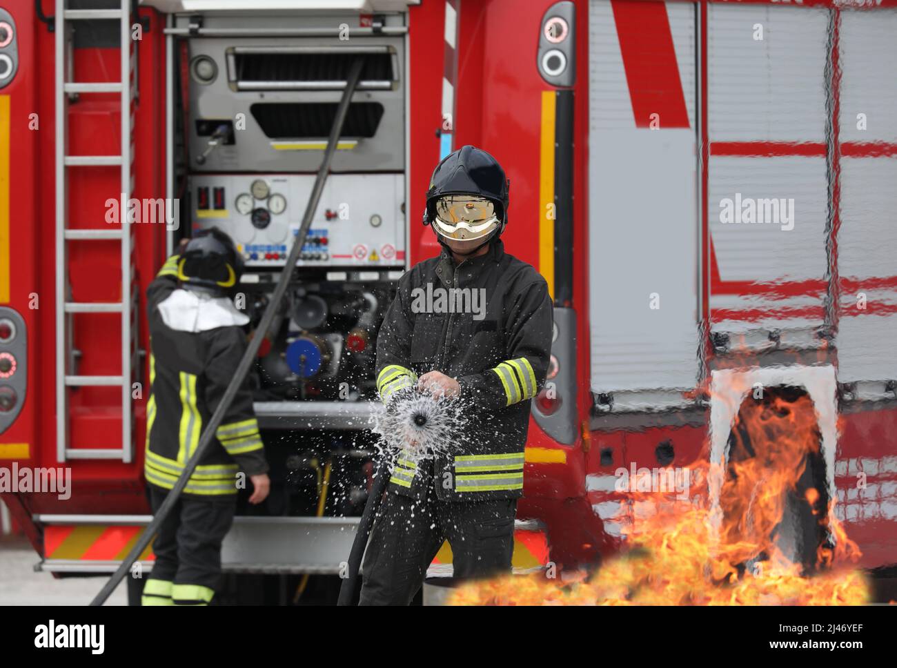 firefighter during a drill extinguishes the fire and the fire truck in ...