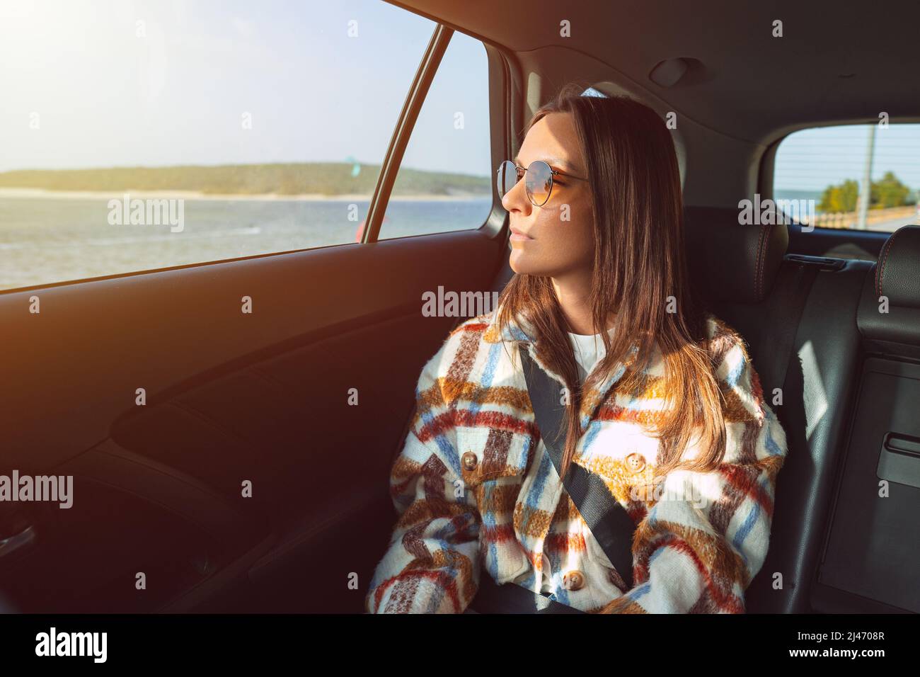 Stylish young woman sitting on back seat in the taxi car and looking ...