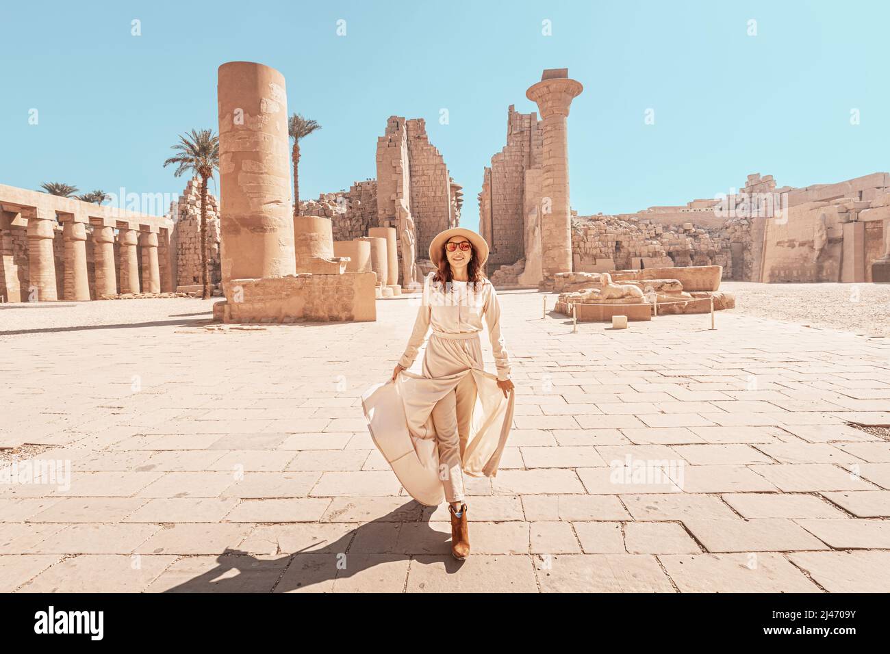 Happy woman traveler explores the ruins of the ancient Karnak temple in ...