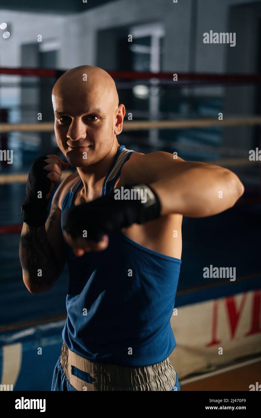 Vertical shot of bald aggressive boxer male wearing bandages punching ...