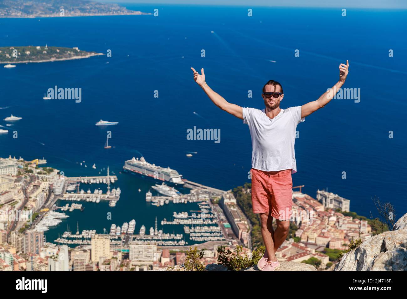 A handsome young man stands and jubilantly with his hands raised on a ...