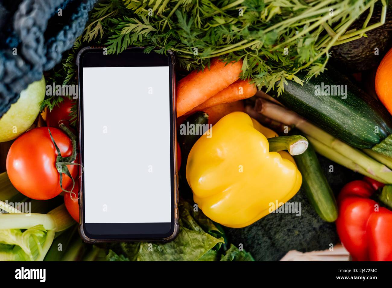 Top view closeup fresh vegetables and phone with blank white screen on ...