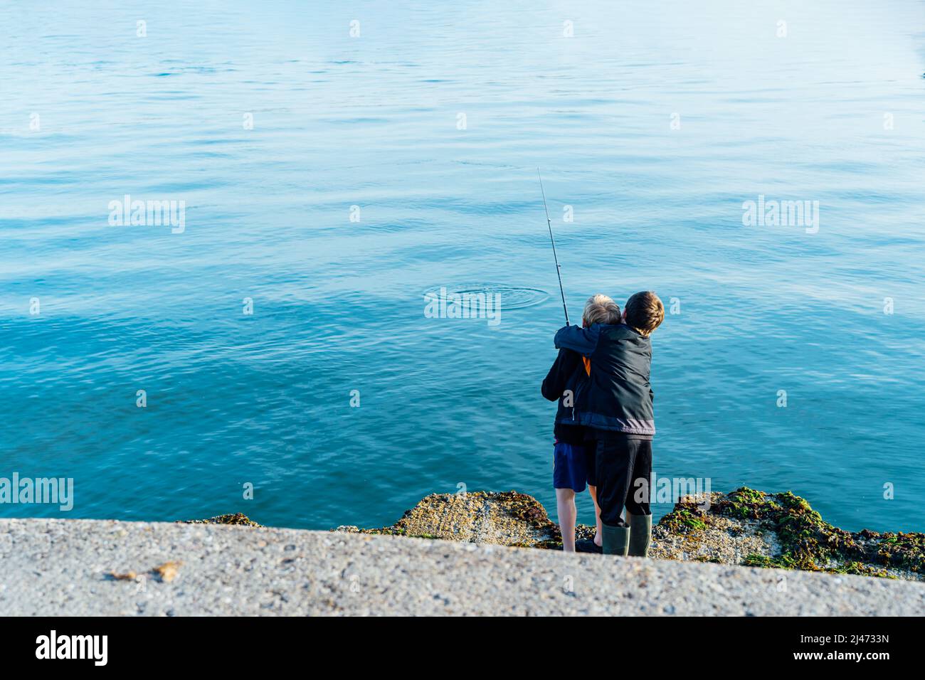 Children fishing. Back view boy teaching fishing his brother or friend ...