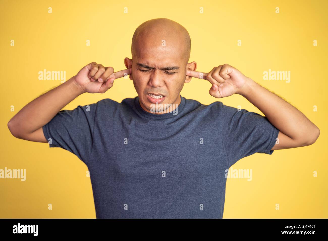 bald man with uncomfortable expression with fingers covering ears Stock ...
