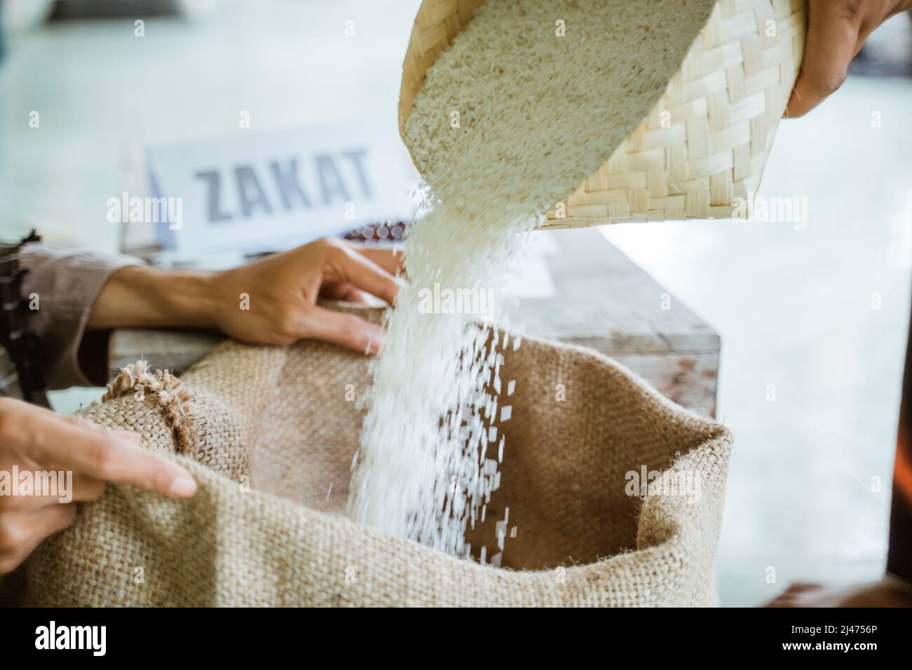 Hands giving rice grains for zakat helping the poor Stock Photo - Alamy