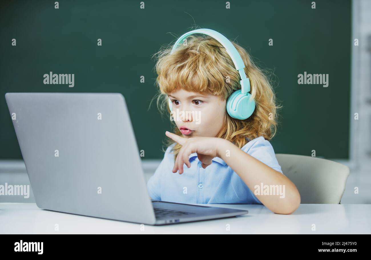 School kids with laptop computer and headphones in class at school ...