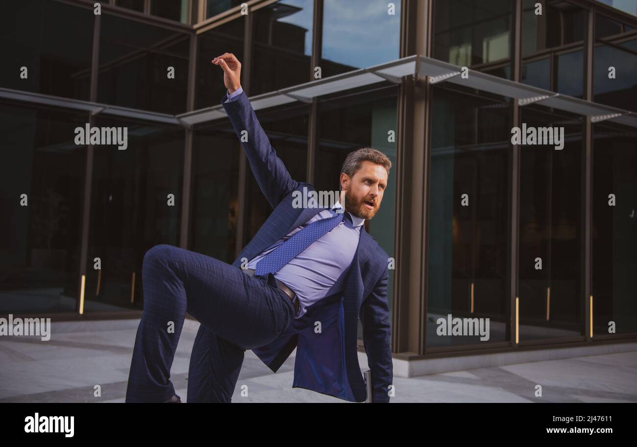 Excited businessman keeping arms raised and expressing positivity while ...