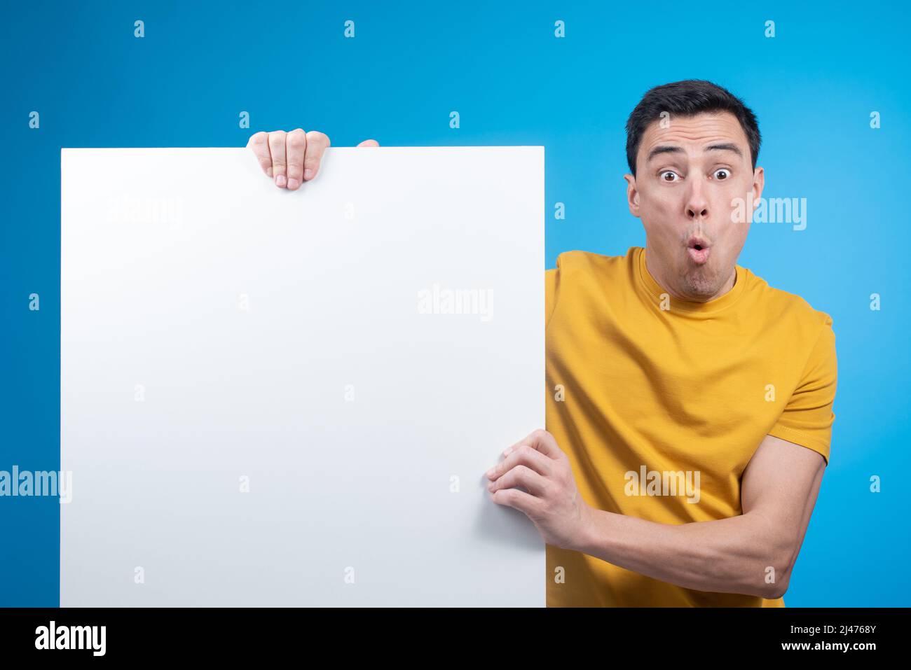 Shocked man showing blank banner in studio Stock Photo - Alamy