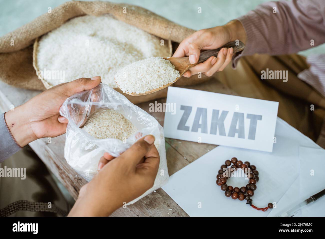 Hands giving rice grains for zakat helping the poor Stock Photo - Alamy