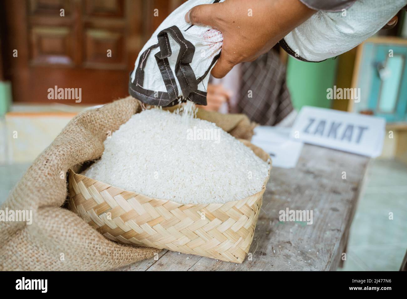 Hands giving rice grains for zakat helping the poor Stock Photo - Alamy
