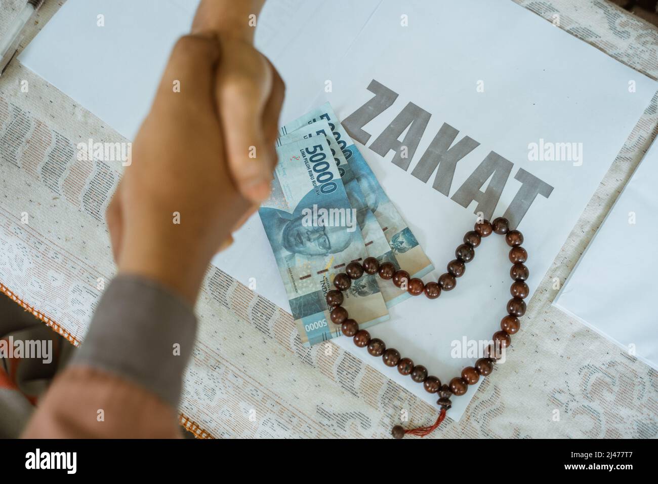 hand shake with money as a payment for zakat donation during ramadan ...
