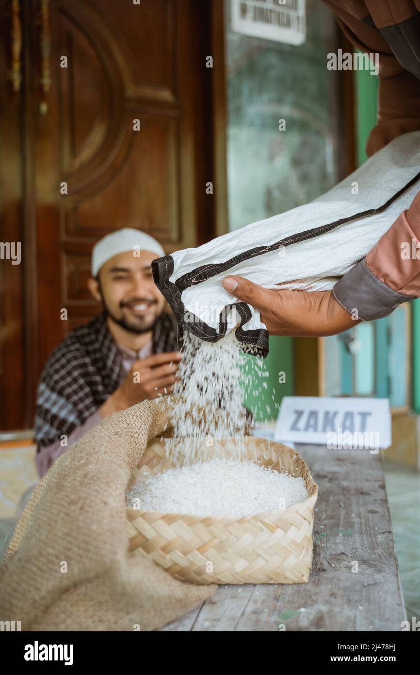Hands giving rice grains for zakat helping the poor Stock Photo - Alamy