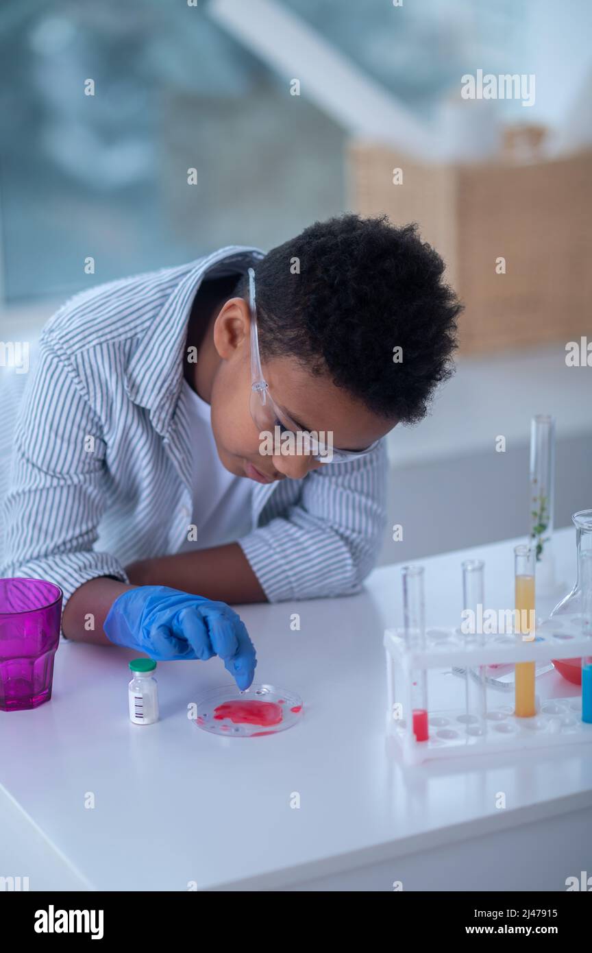 A boy in a lab coat working with test tubes and looking involved Stock ...