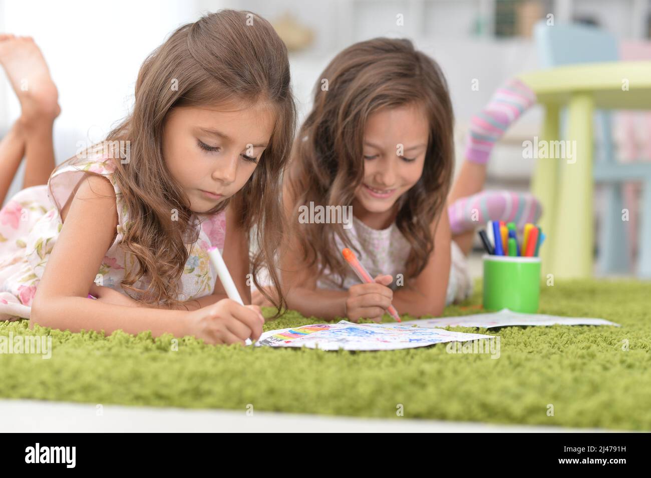 Two cute little girls drawing with pencils Stock Photo - Alamy