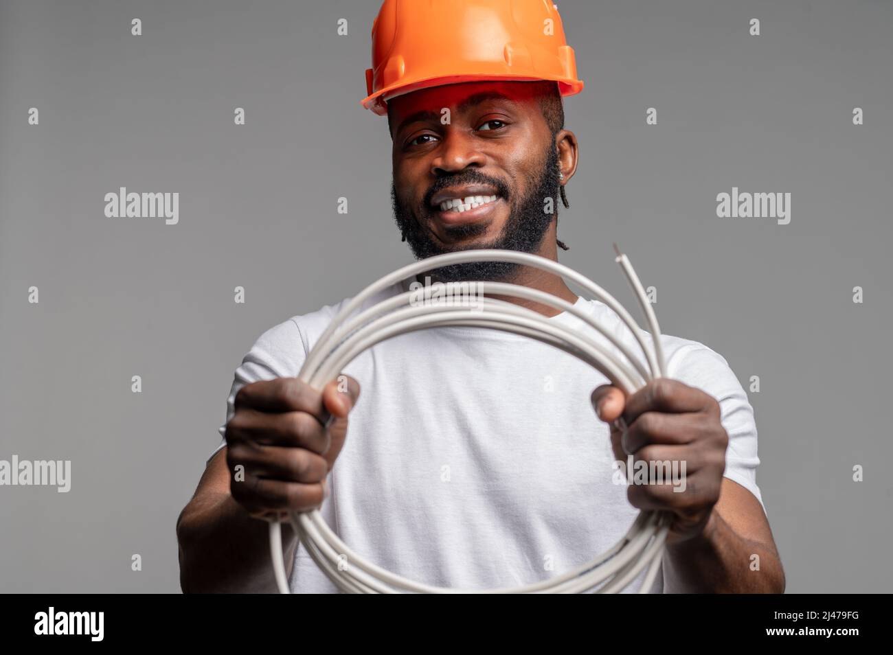 Engineer in an orange helmet demonstrating a rubber-sheathed electrical ...