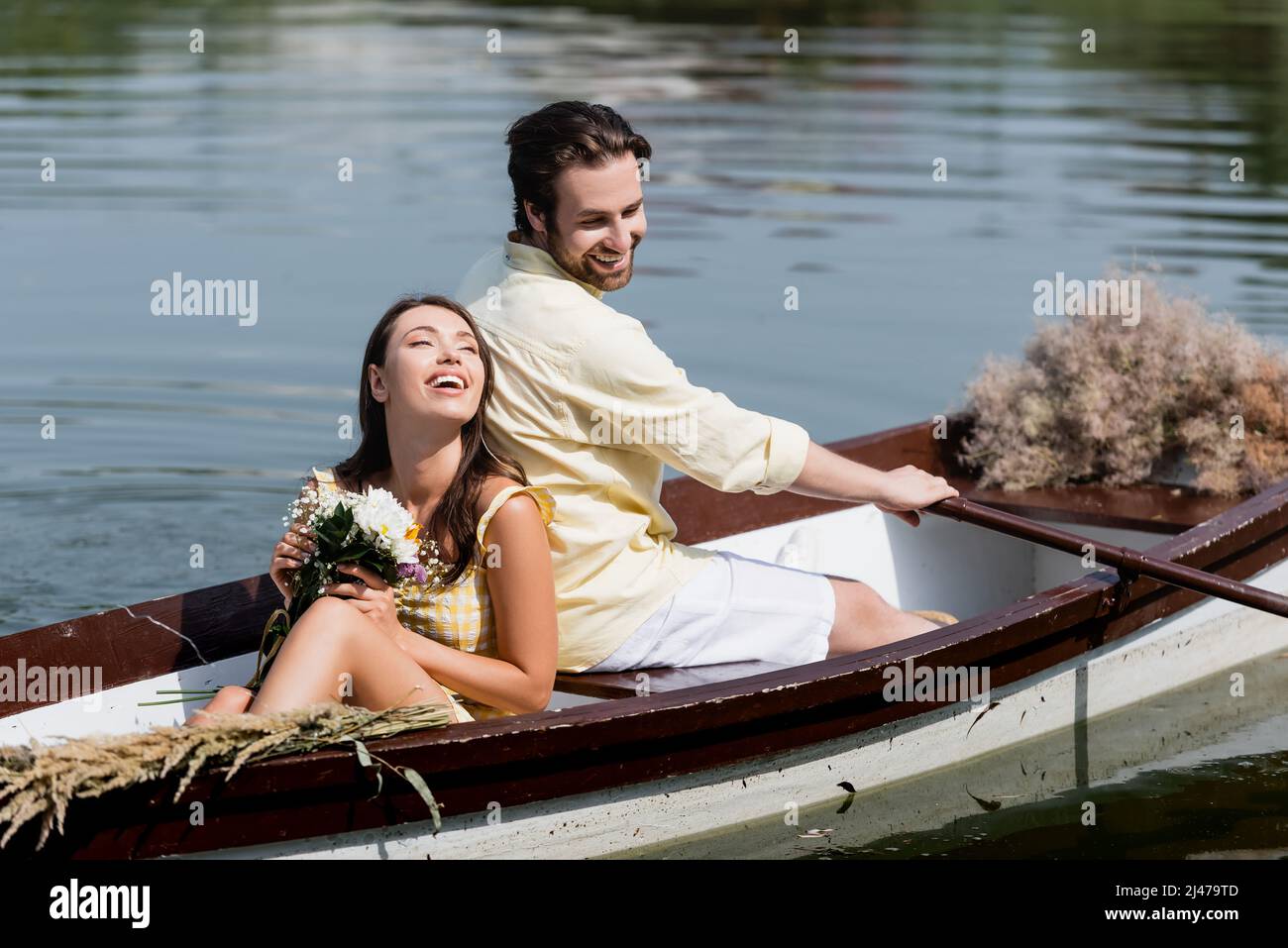 happy young woman holding flowers and leaning on back of boyfriend ...