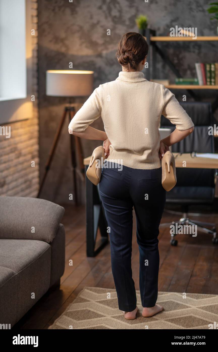 A woman standing backside with beige shoes in hands Stock Photo - Alamy