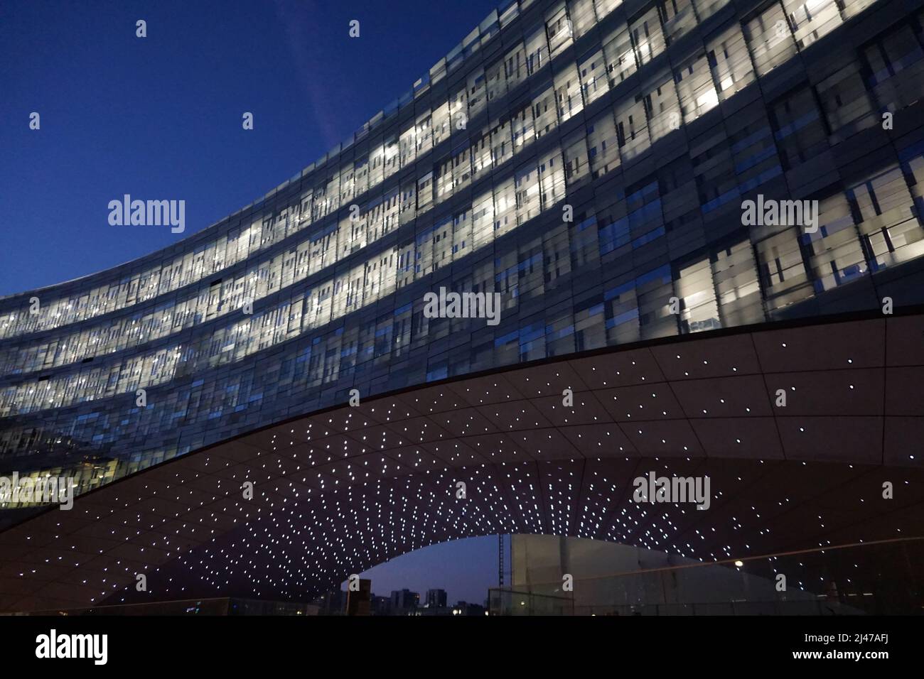 view of an unusual lighted glass round building in downtown Paris ...