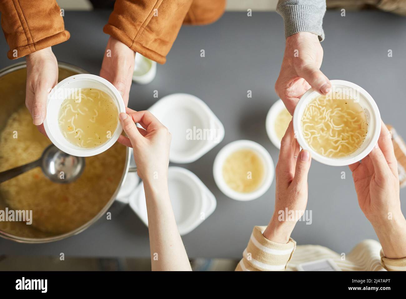 Top view close up of volunteers giving out simple meals to people in ...