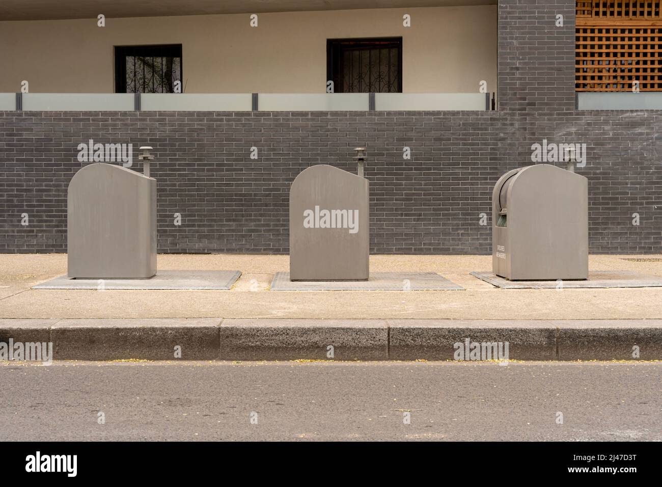 Buried trash can in front of a brown wall Stock Photo - Alamy