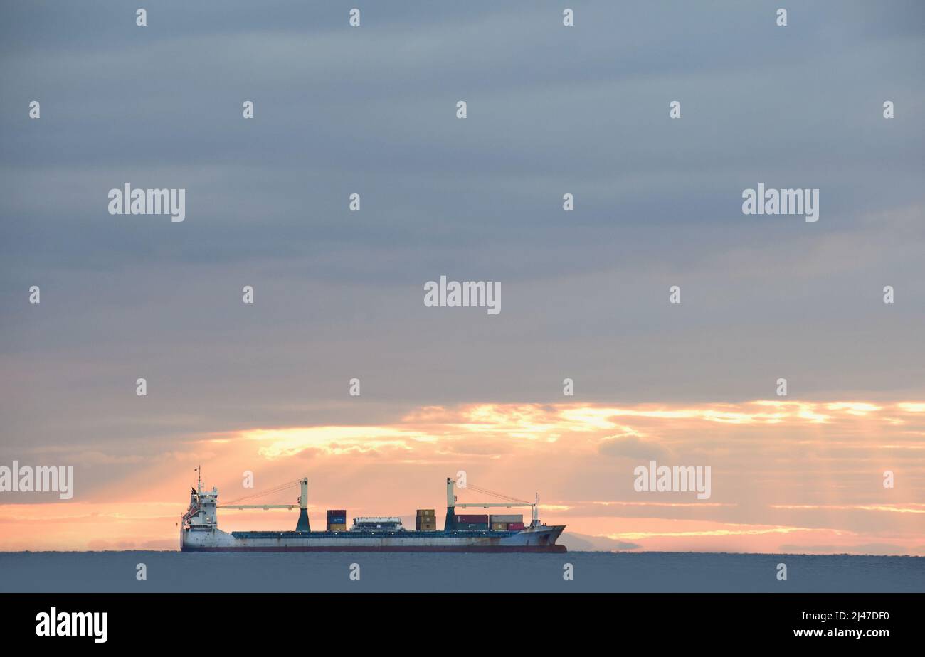 Cargo ship at sunset. Old ship at Aegean sea and beautiful clouds Stock ...