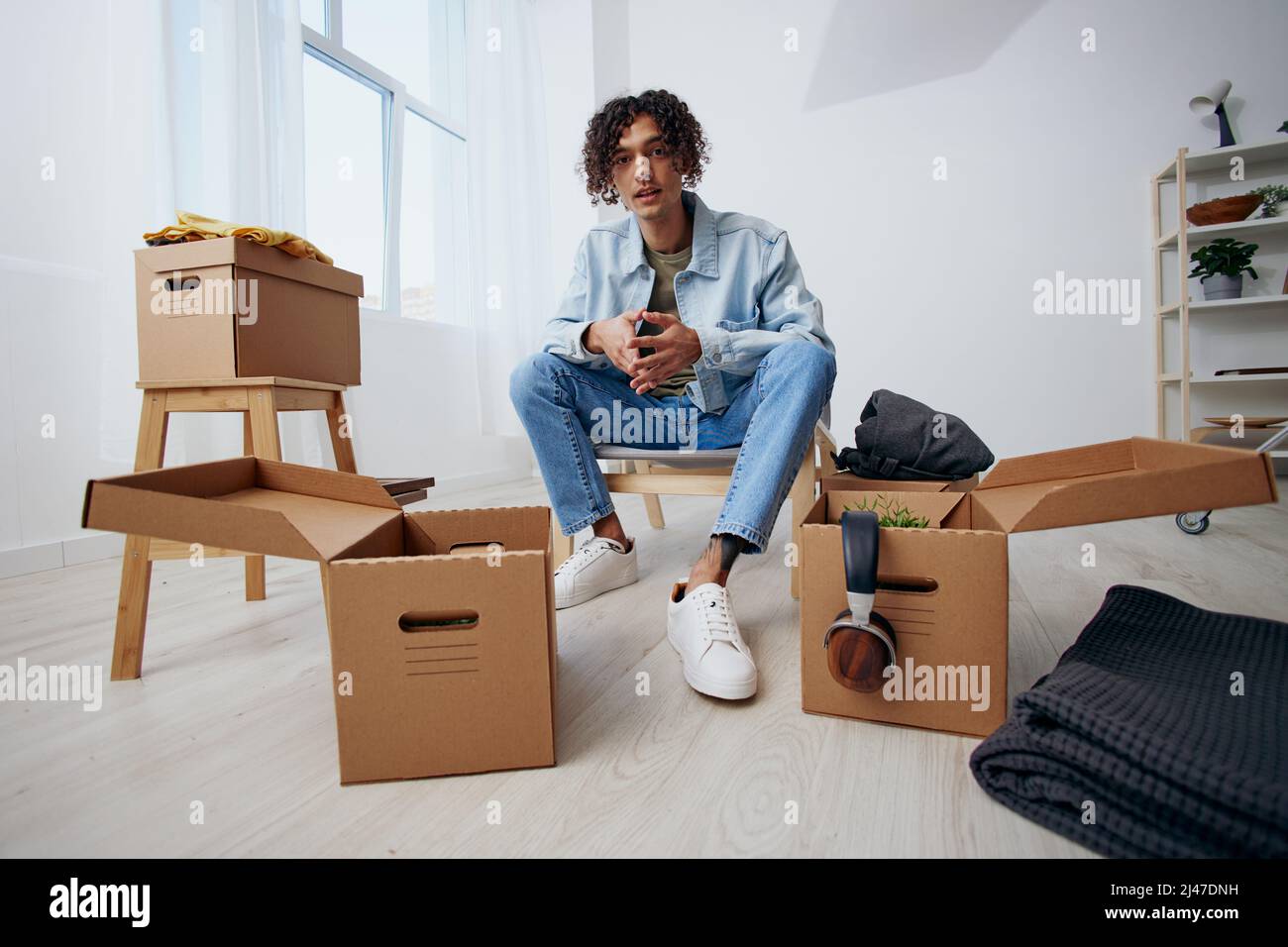 handsome guy sitting on a chair with boxes moving interior Stock Photo ...