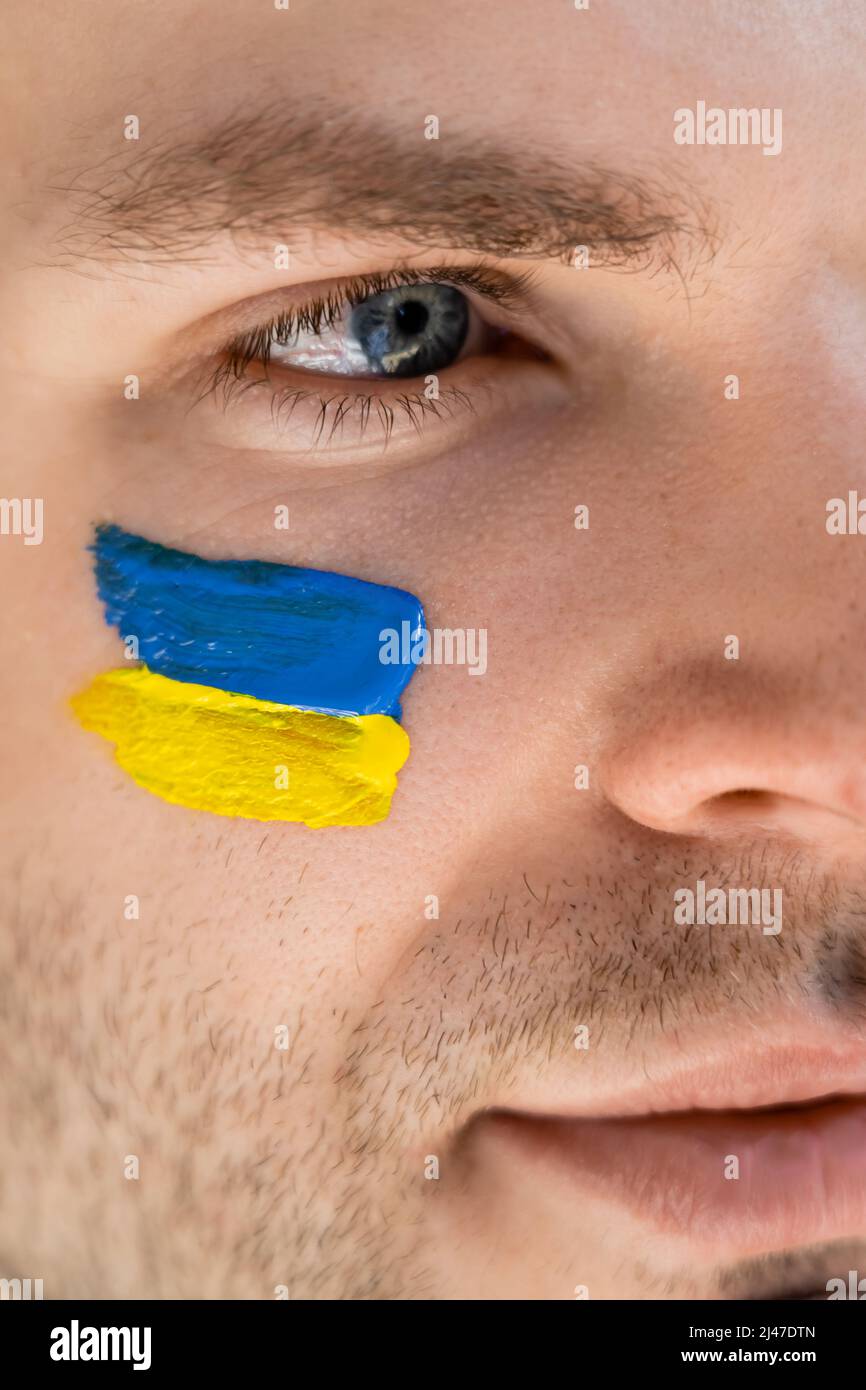 close up view of ukrainian flag painted on face of young patriotic man ...
