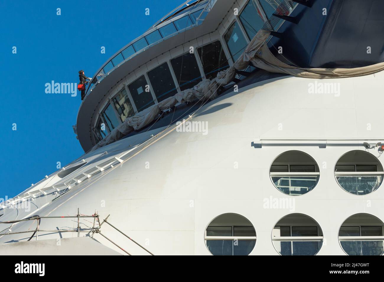 Shipyard workers are seen in acrobatic positions as they work on the ...