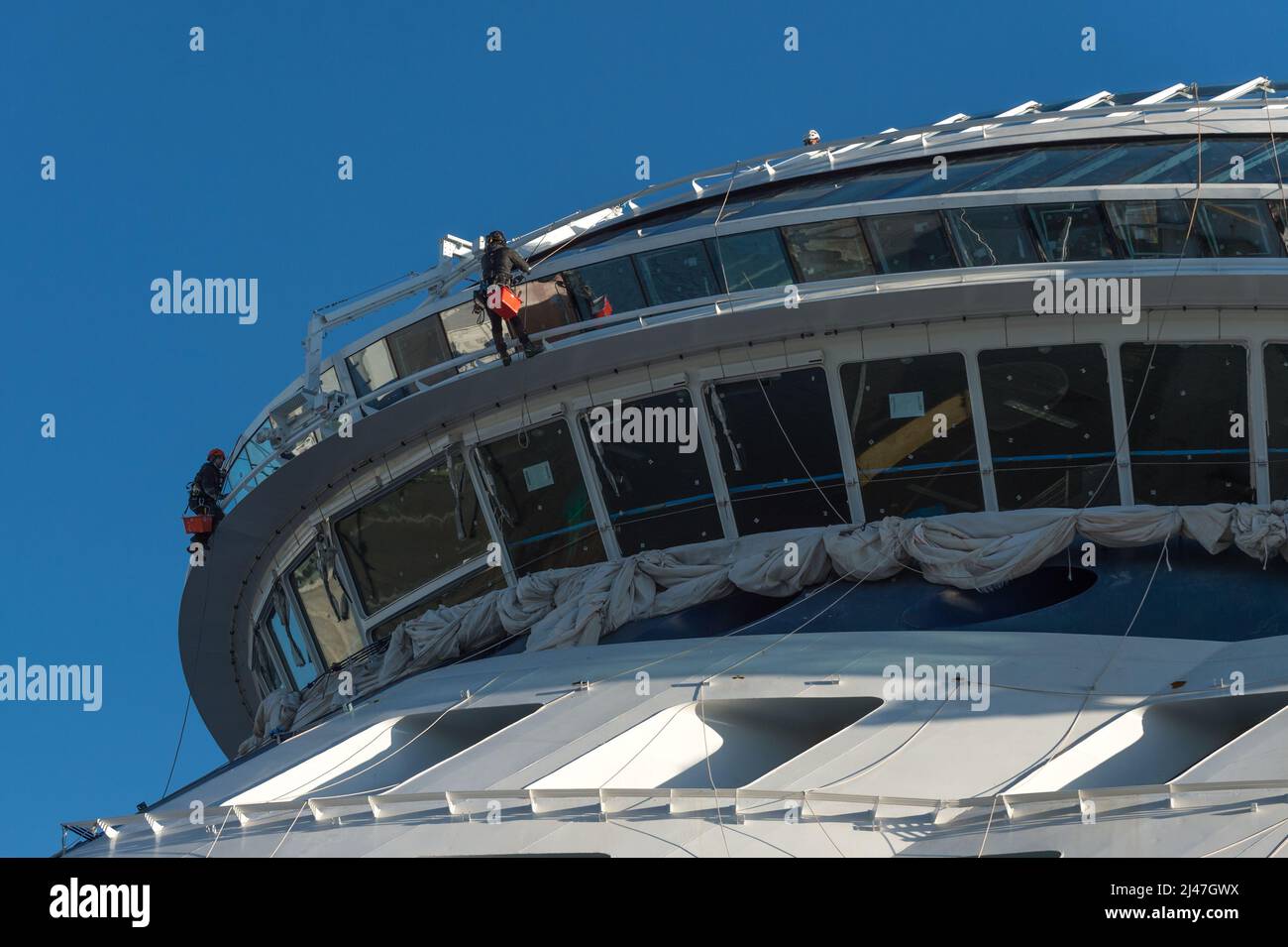 Shipyard workers are seen in acrobatic positions as they work on the ...
