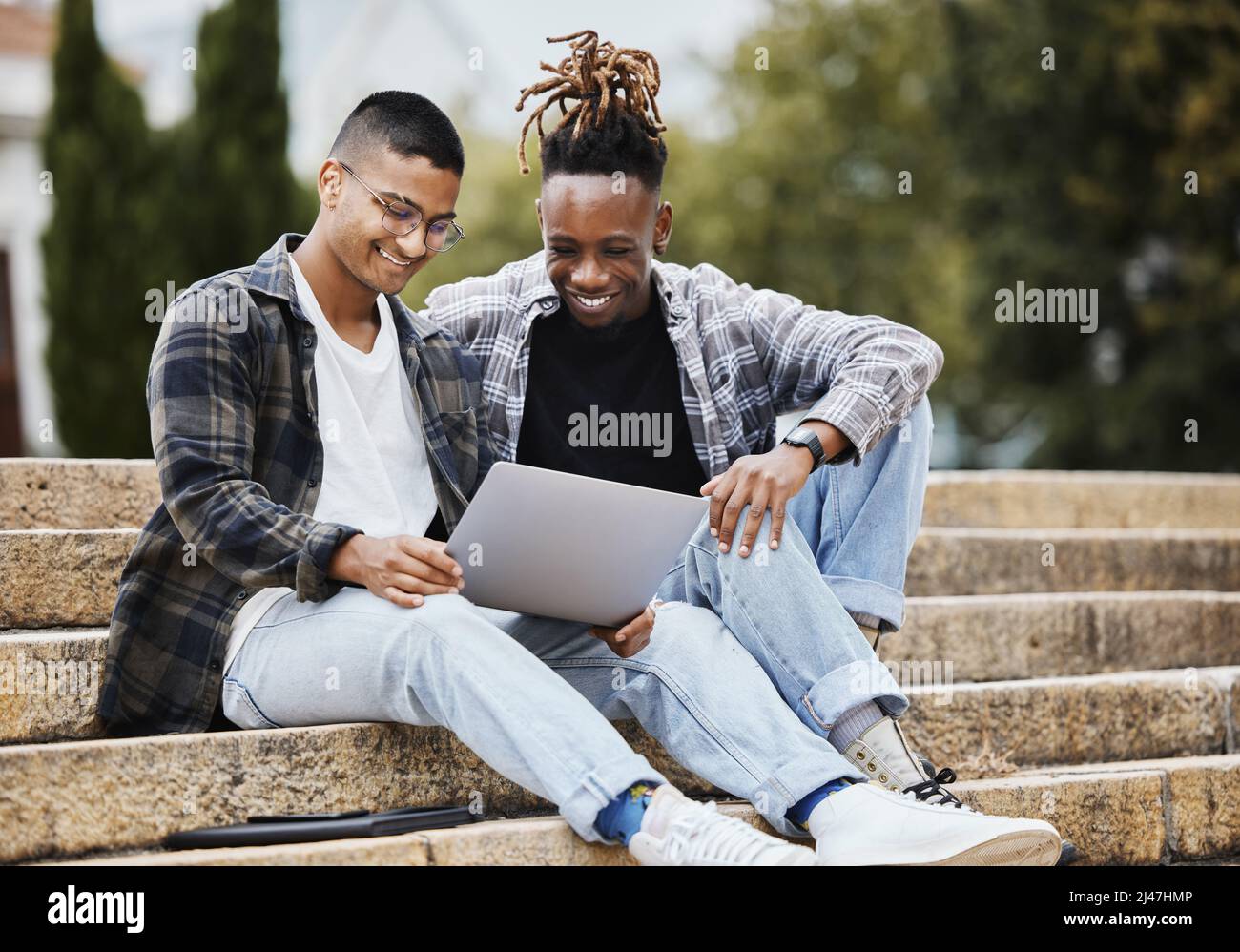 Work hard now so you can play hard later. Shot of two young men using a ...