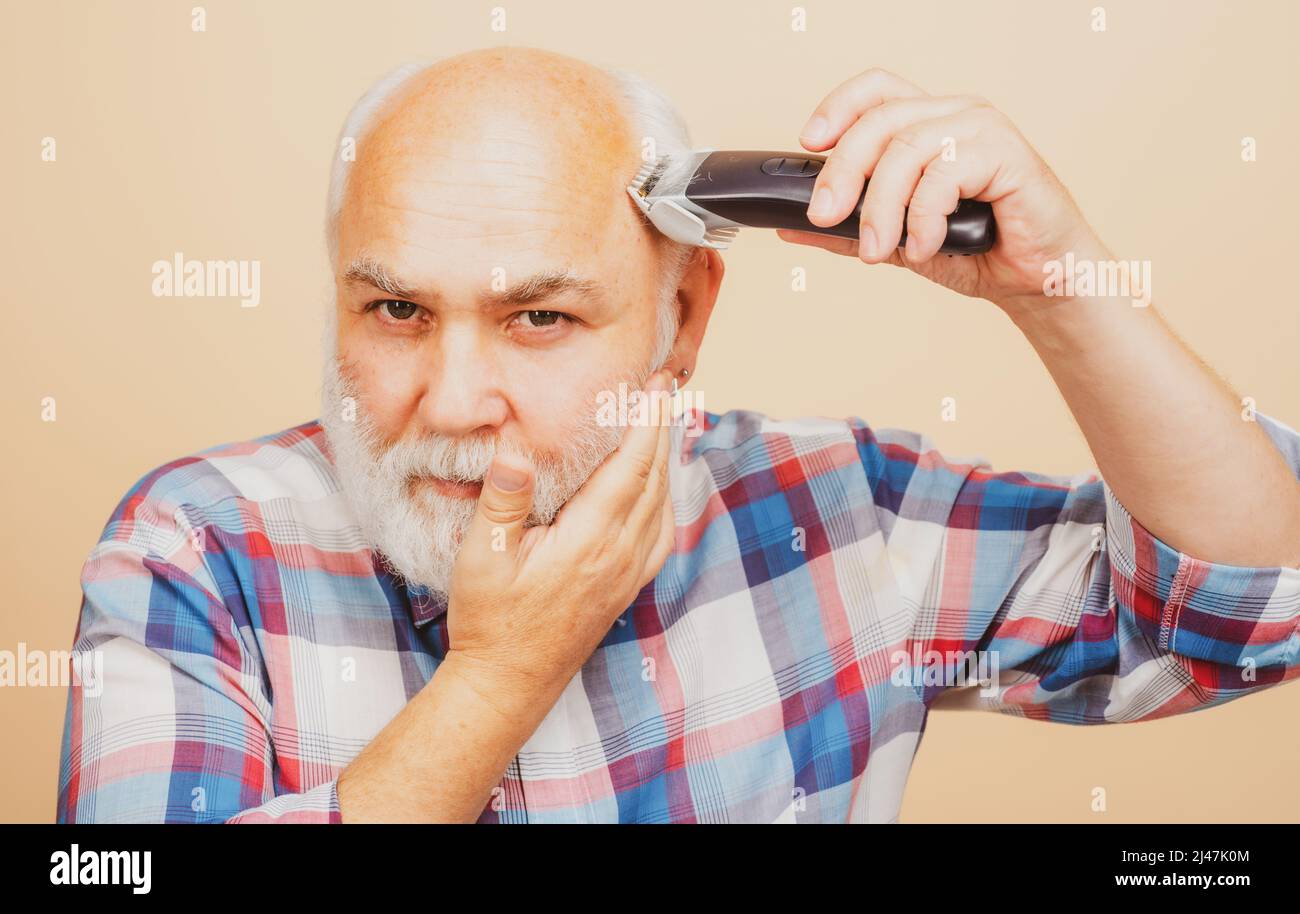 Senior hairdresser man with hair clipper, haircut with an electric ...