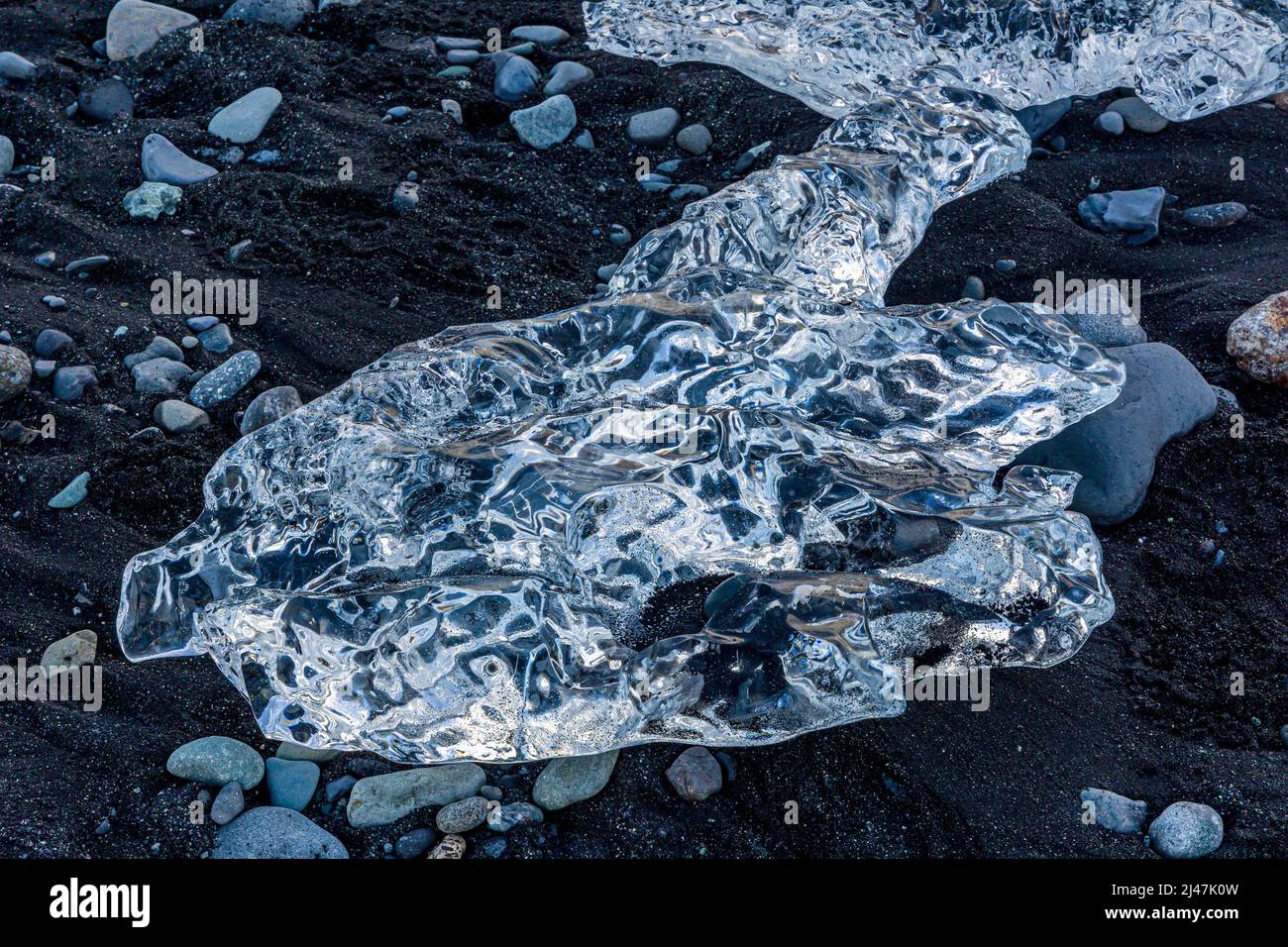 Beautiful blue icebergs and chunks of ice washed up on a volcanic black ...