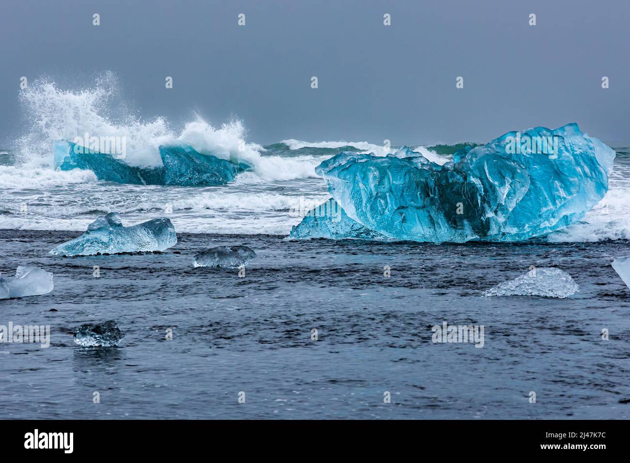 Ocean waves breaking over icebergs and large chunks of blue ice on a ...