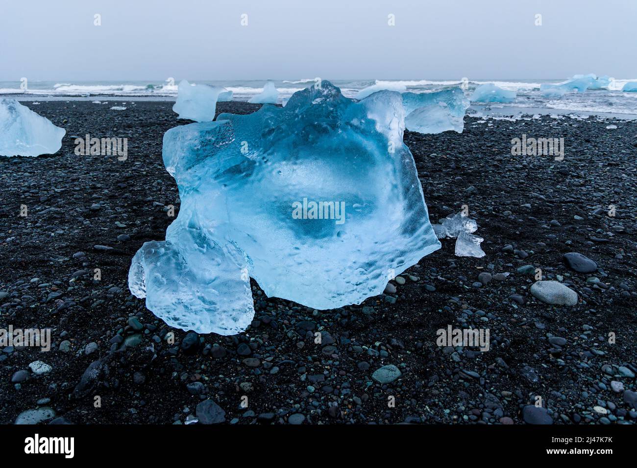 Beautiful blue icebergs and chunks of ice washed up on a volcanic black ...