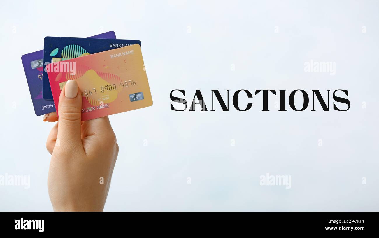 Hand with credit cards and word SANCTIONS on white background Stock ...