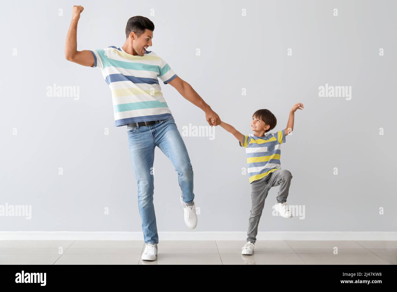 Happy dancing man and his son on light background Stock Photo - Alamy