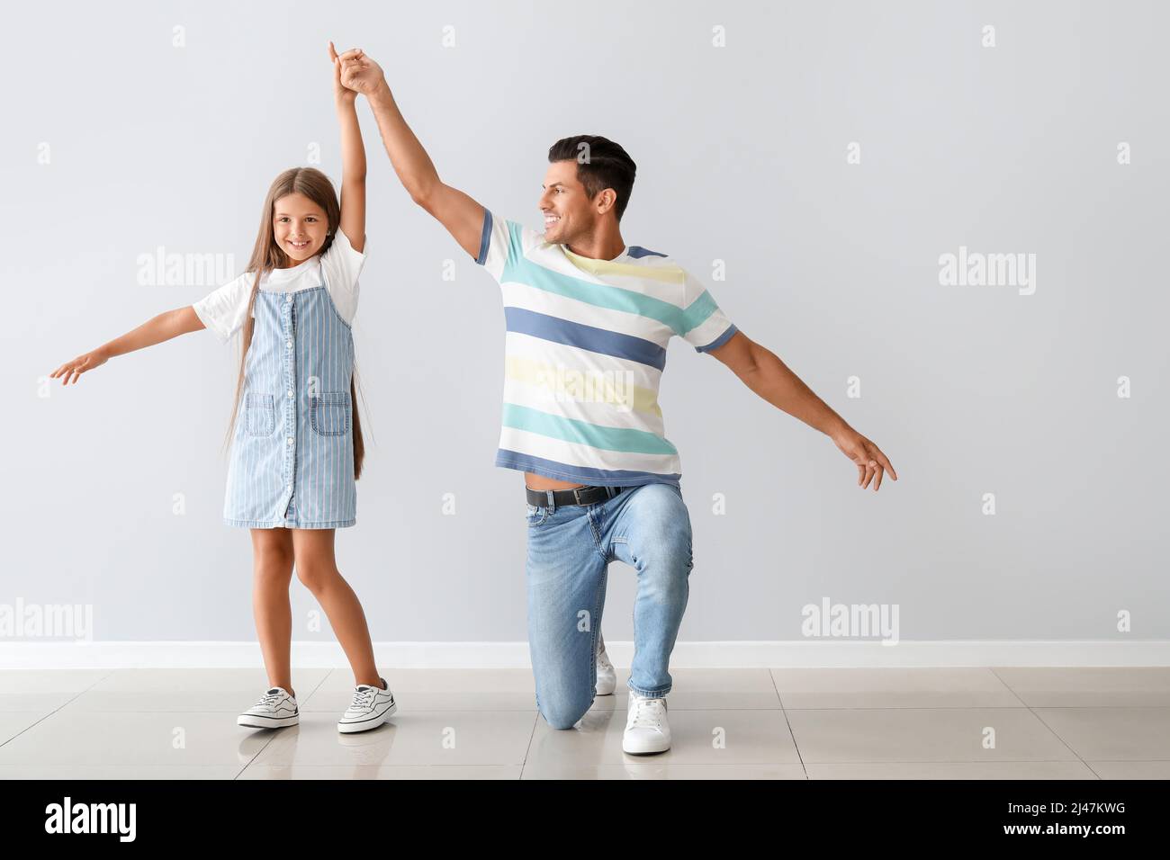 Happy dancing man and his daughter on light background Stock Photo - Alamy