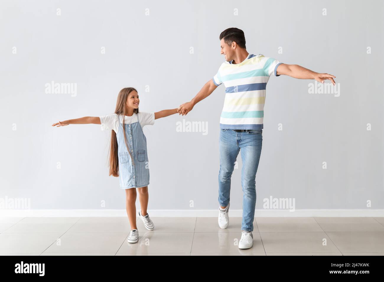 Happy dancing man and his daughter on light background Stock Photo - Alamy
