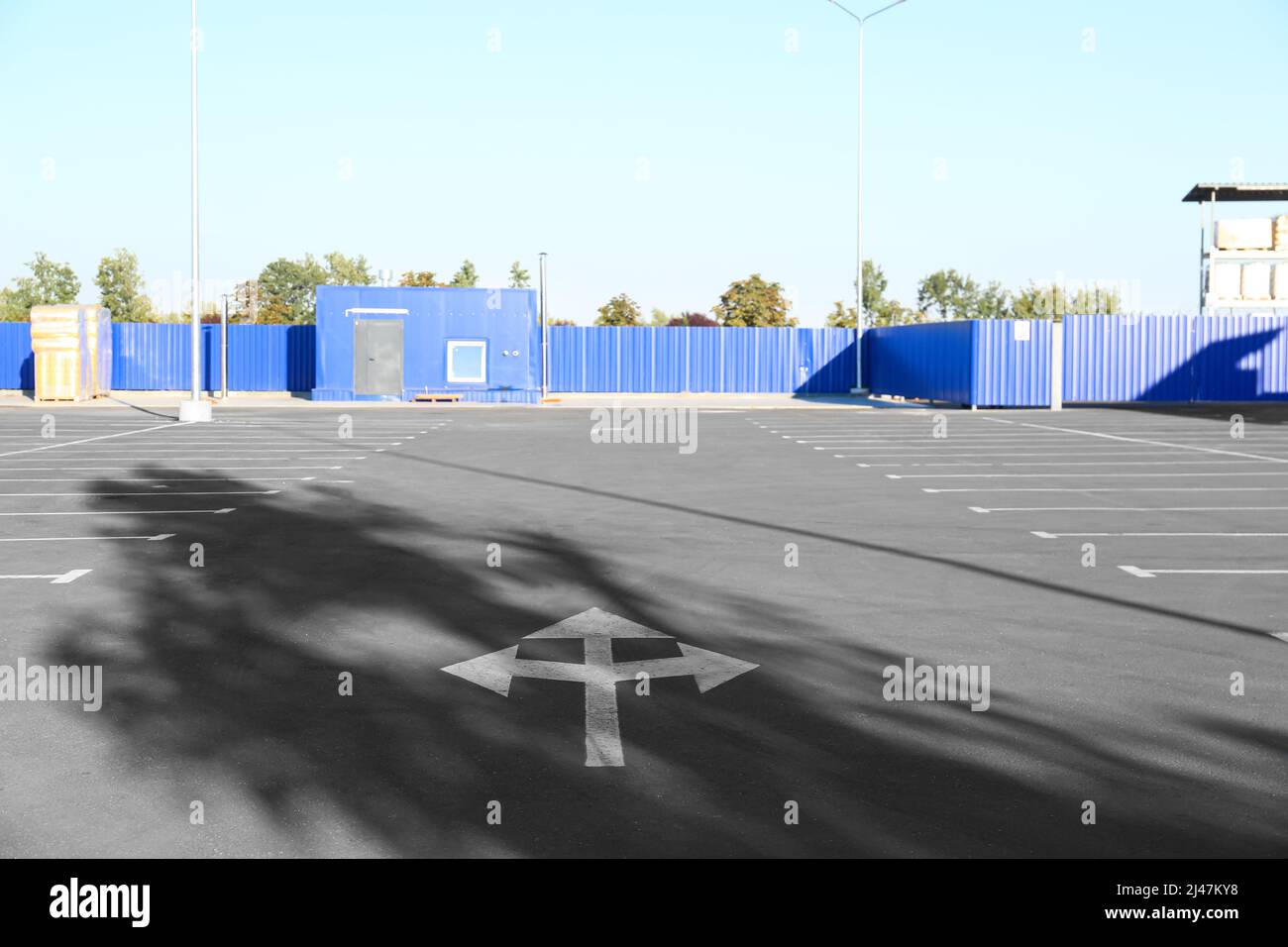 Empty parking lot on blue fencing background Stock Photo - Alamy