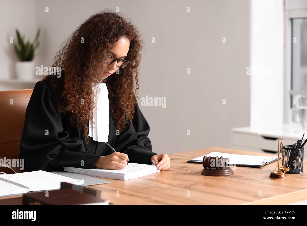 Female judge signing documents at workplace in courtroom Stock Photo ...