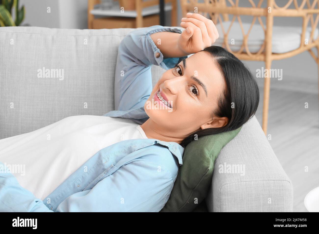 Beautiful woman with dental braces lying on sofa at home Stock Photo ...