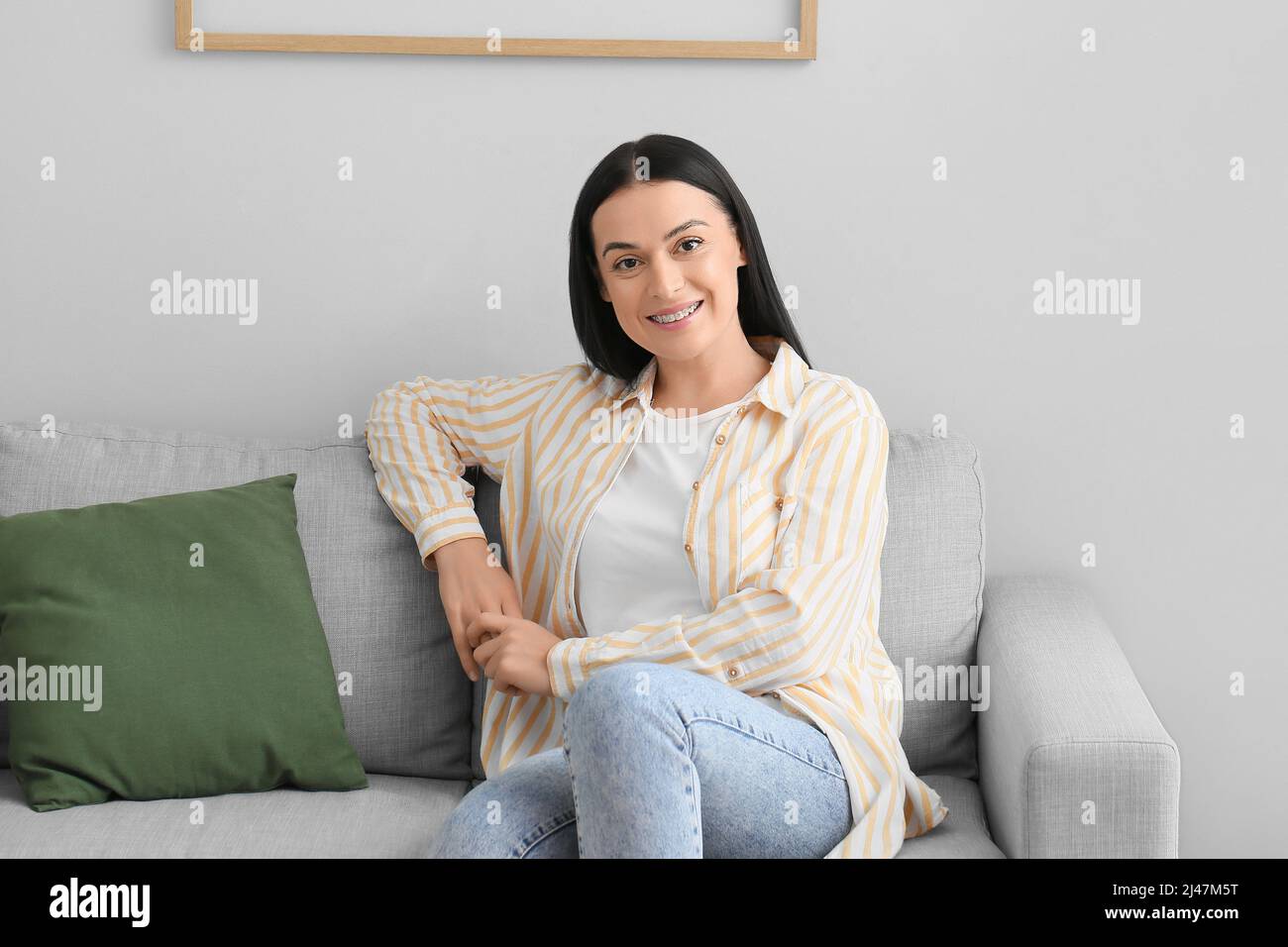 Beautiful woman with dental braces sitting on sofa at home Stock Photo ...
