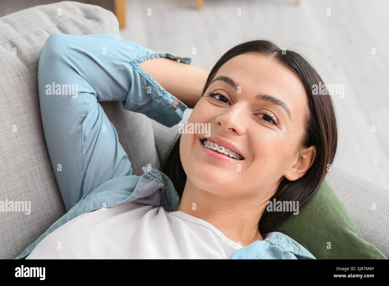 Beautiful woman with dental braces lying on sofa at home, closeup Stock ...