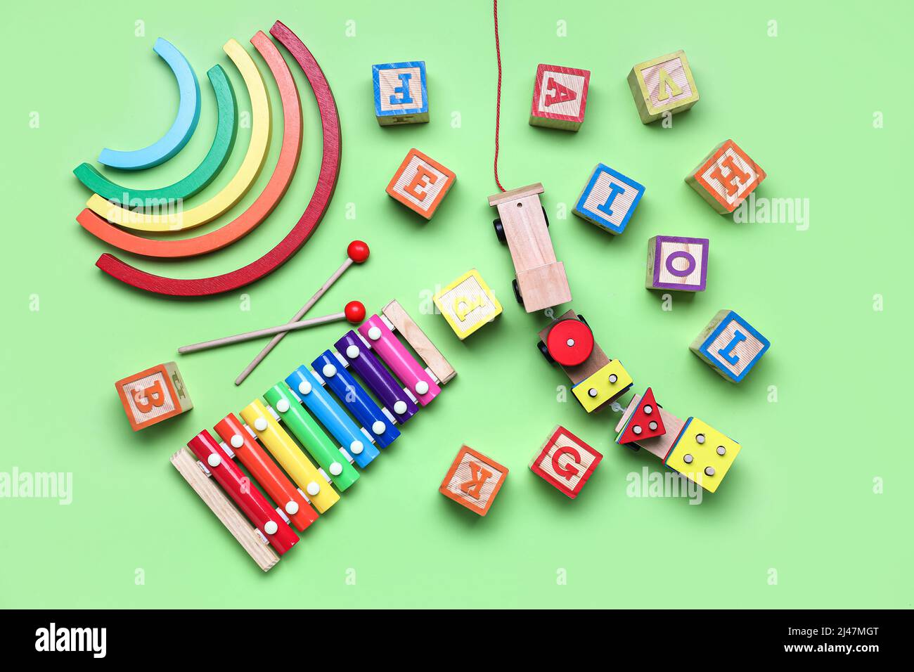 Wooden cubes with letters, blocks and xylophone on green background ...