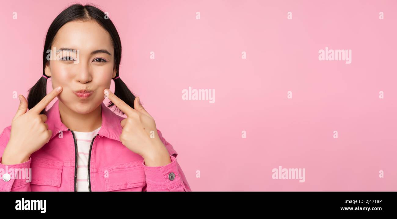 Close up portrait of young asian girl showing her dimples, poking ...